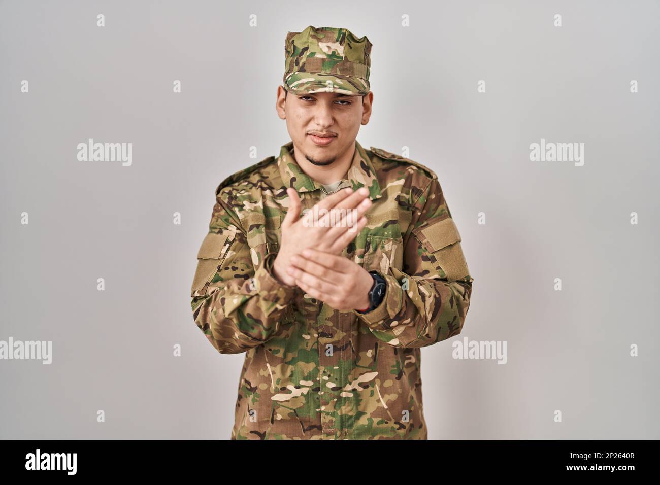 Young arab man wearing camouflage army uniform suffering pain on hands ...
