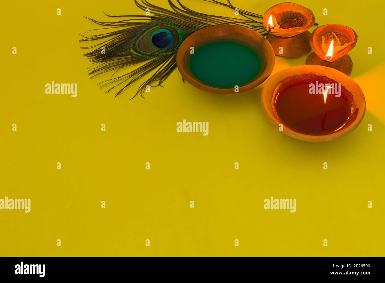 happy holi celebration with colors, clay lamp and peacock feather ...