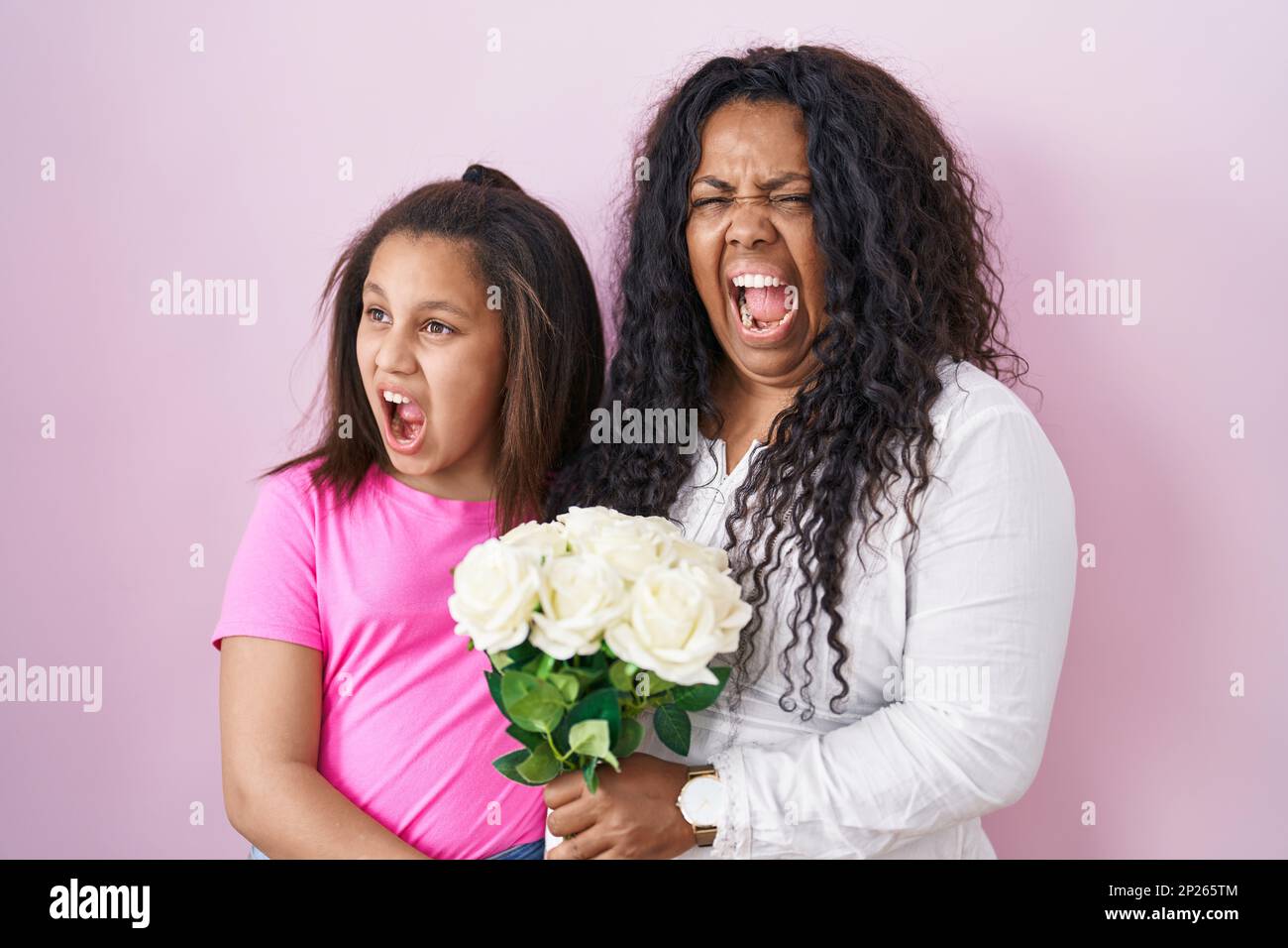 Mother and young daughter holding bouquet of white flowers angry and ...