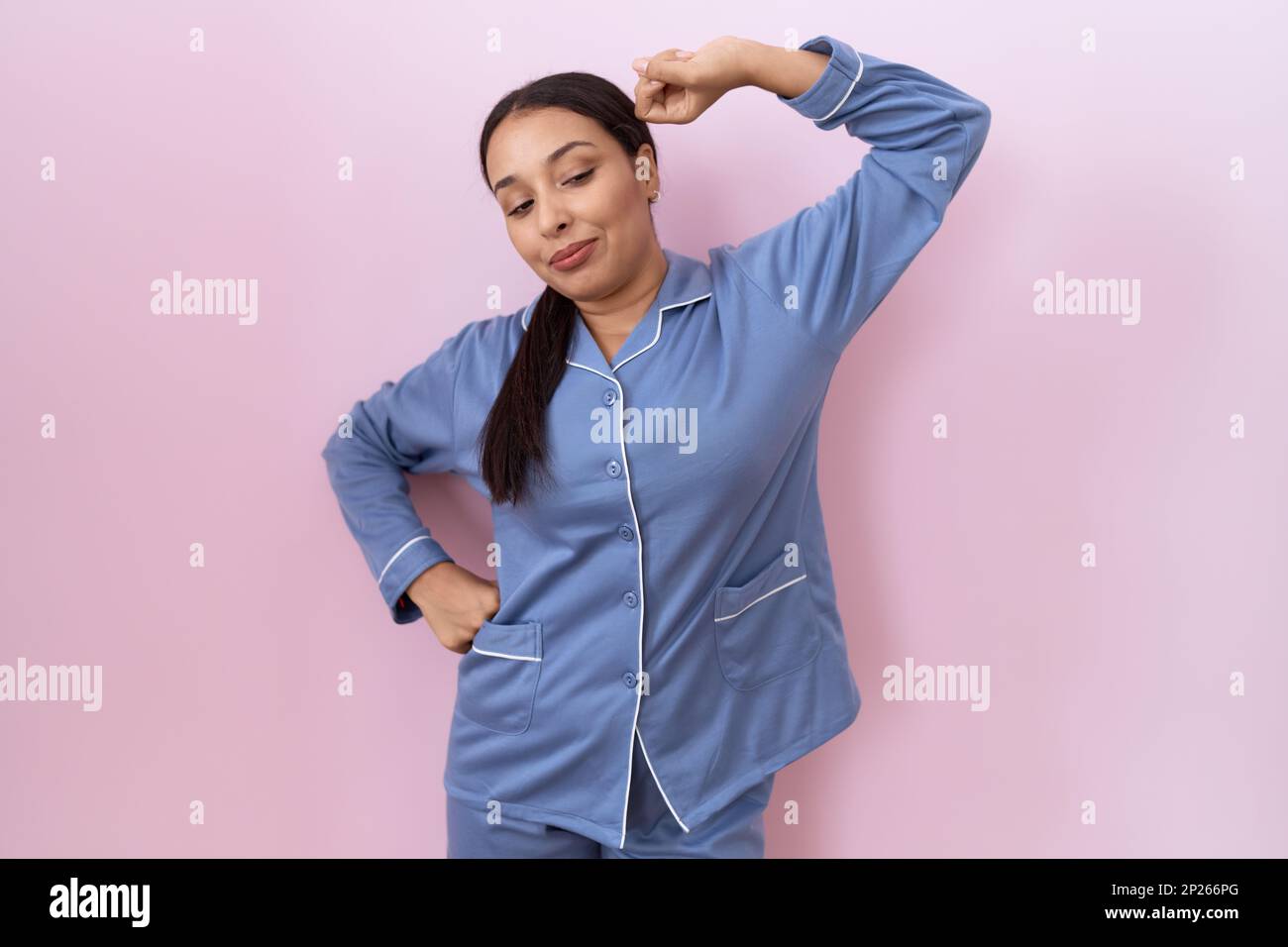 Young arab woman wearing blue pajama stretching back, tired and relaxed ...