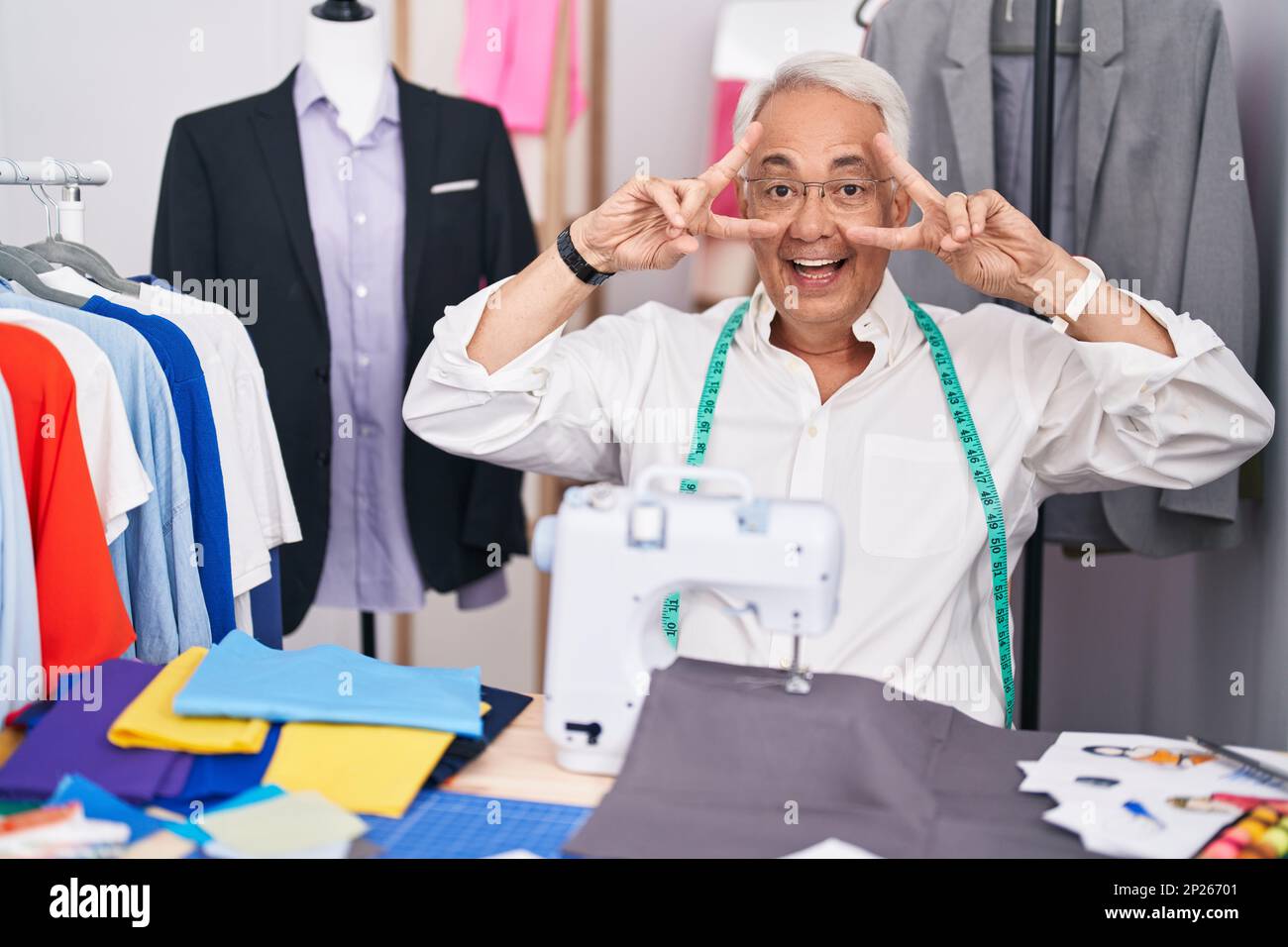 Middle age man with grey hair dressmaker using sewing machine doing ...