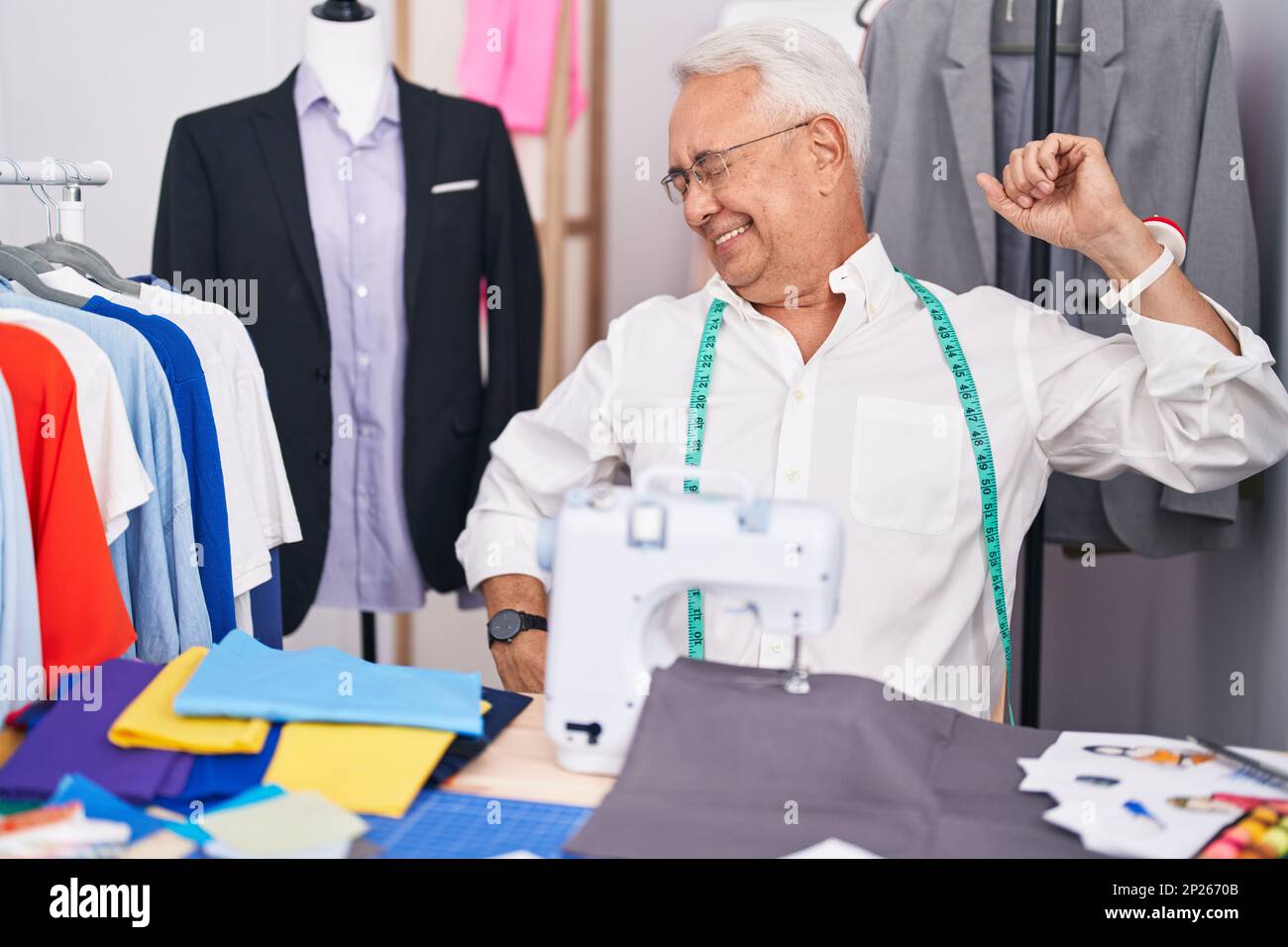 Middle age man with grey hair dressmaker using sewing machine ...