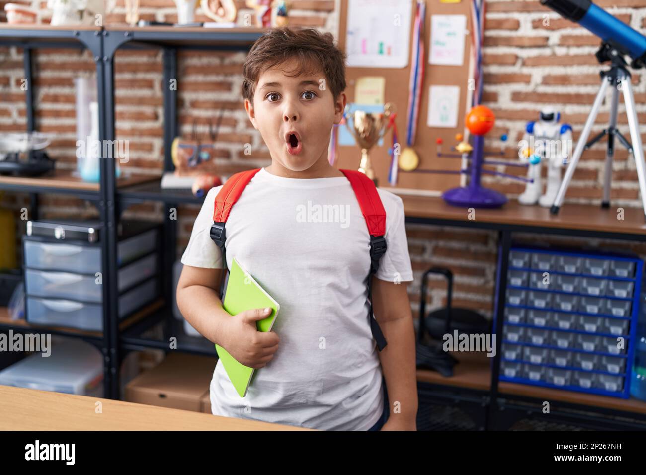 Little hispanic boy wearing student backpack and holding book at school ...