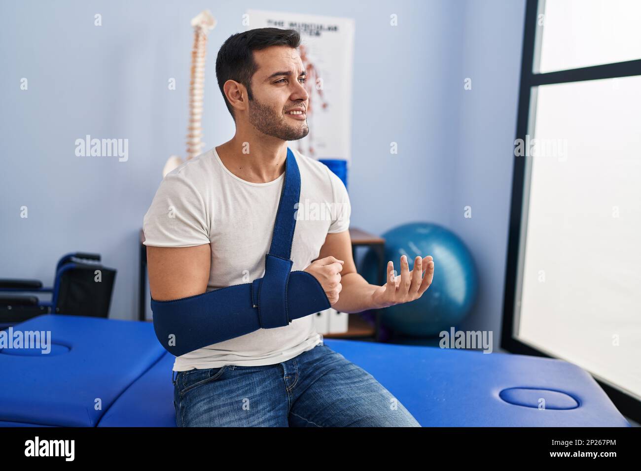 Young hispanic man injured physiotherapy patient suffering for arm pain ...