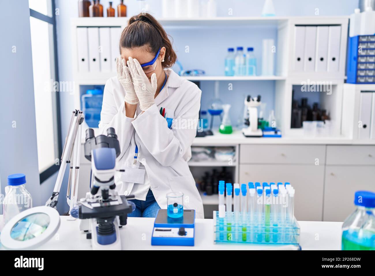 Young hispanic woman working at scientist laboratory with sad ...