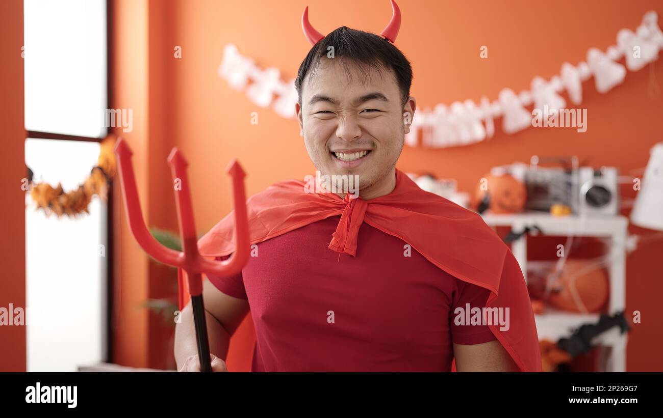 Young chinese man wearing devil costume holding trident at home Stock ...