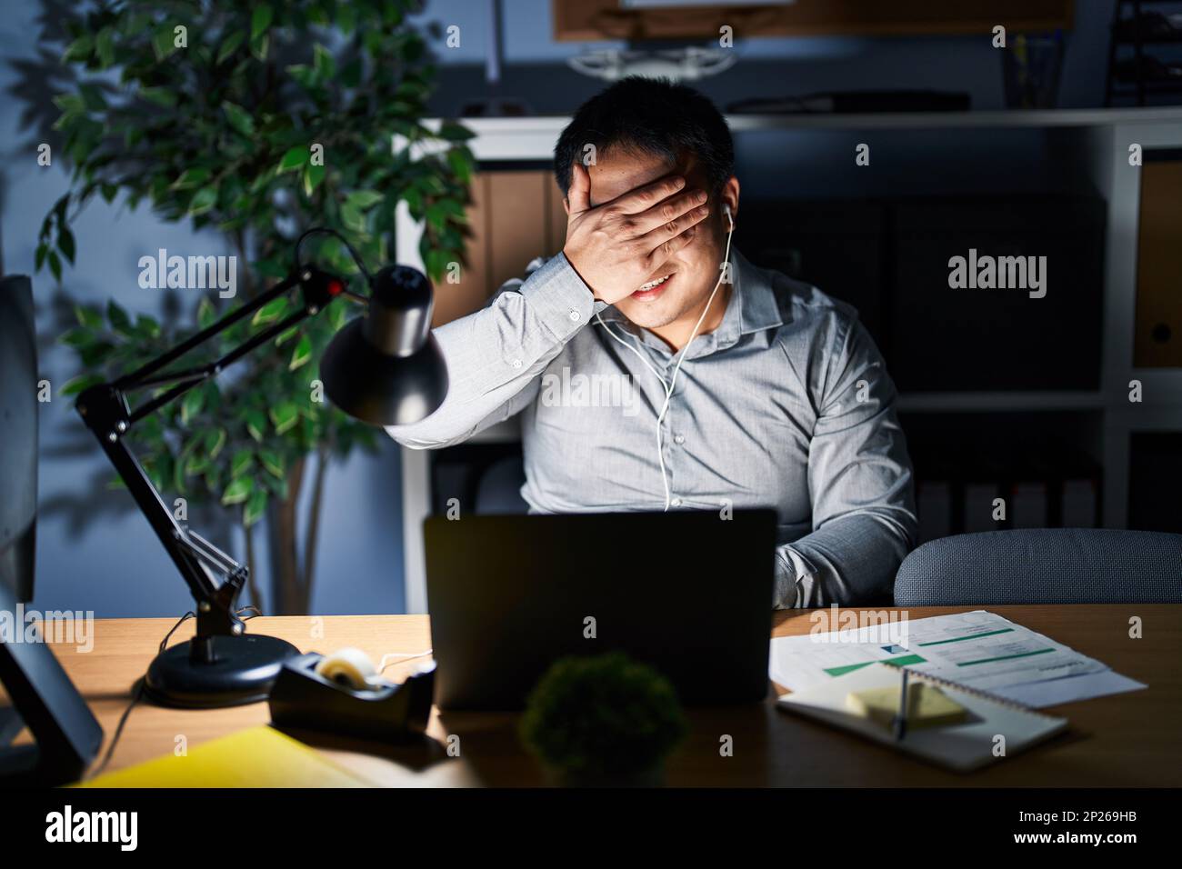 Young chinese man working using computer laptop at night smiling and ...