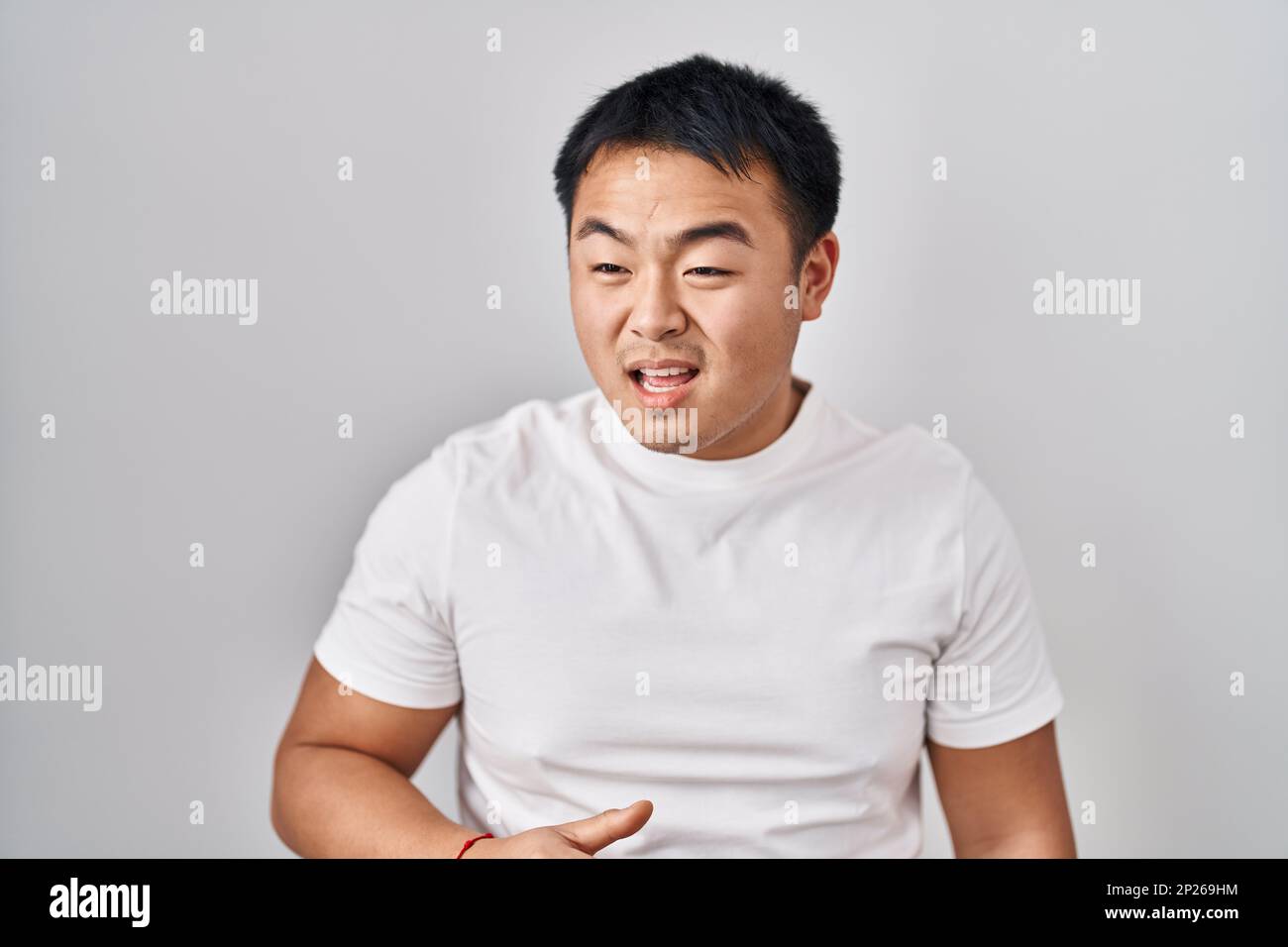Young chinese man standing over white background angry and mad ...