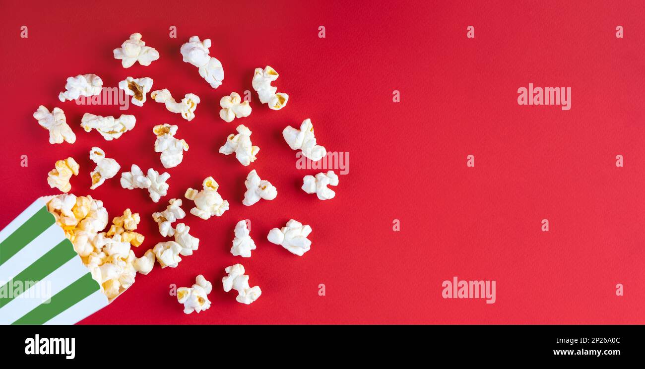 Tasty cheese popcorn falling out of a green striped carton bucket ...