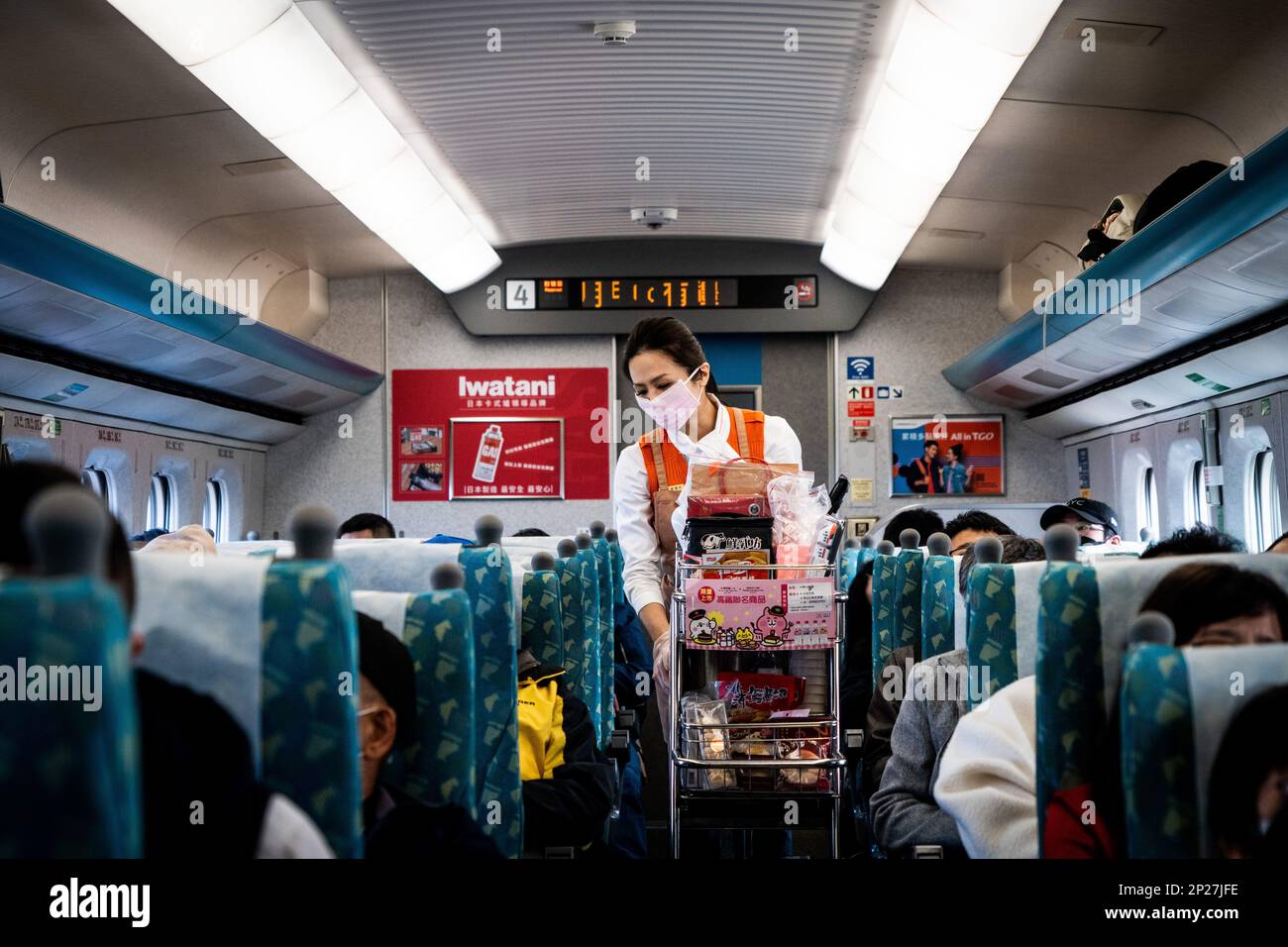 A railway worker with a snack cart sells sundries to passengers on the ...