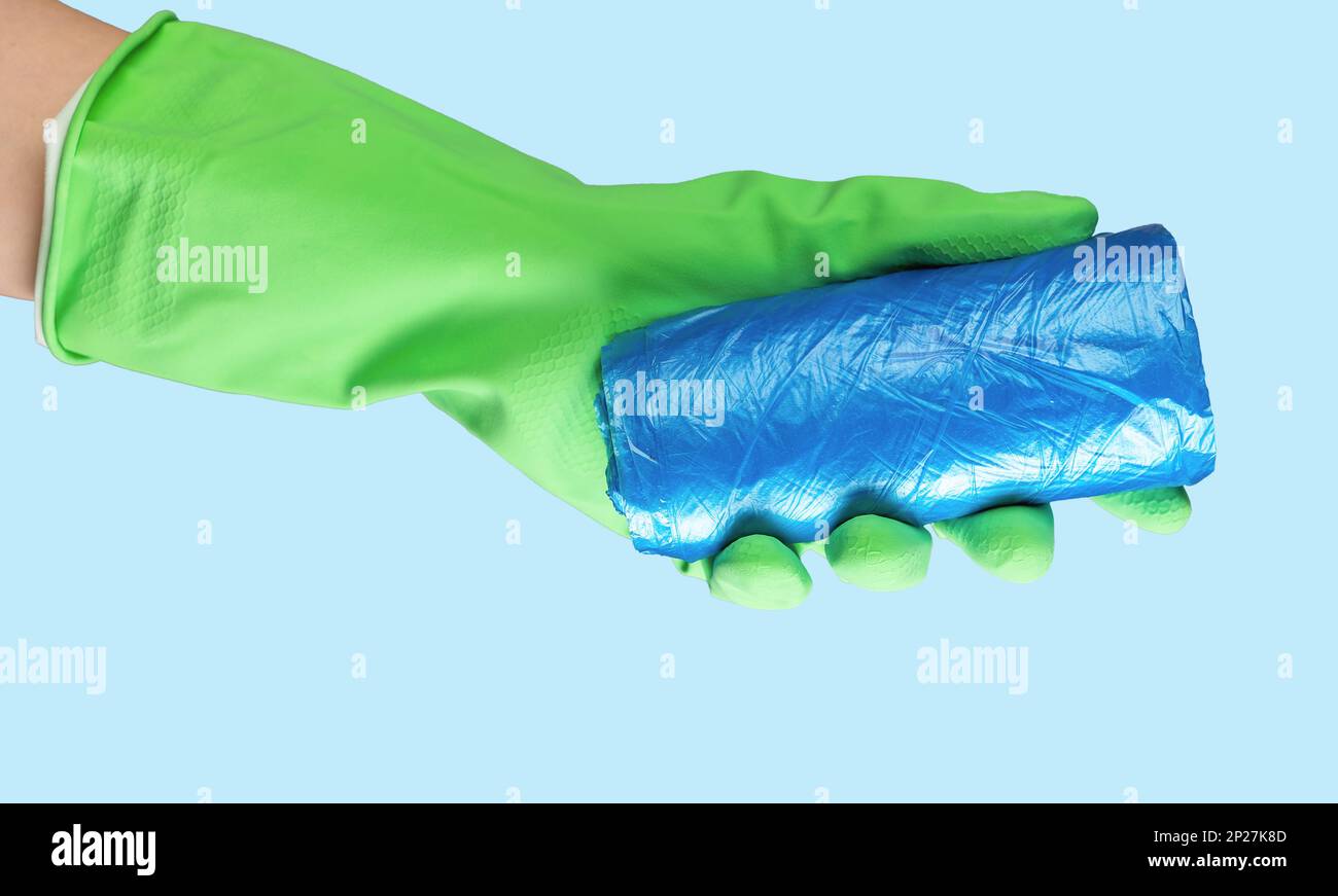 Garbage trash bag roll in hand in green glove, new polyethylene plastic ...