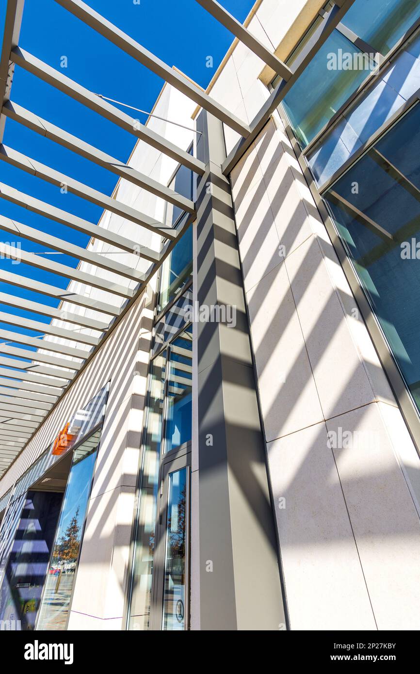 Striped shadows and sunlight from overhead structure on modern building ...