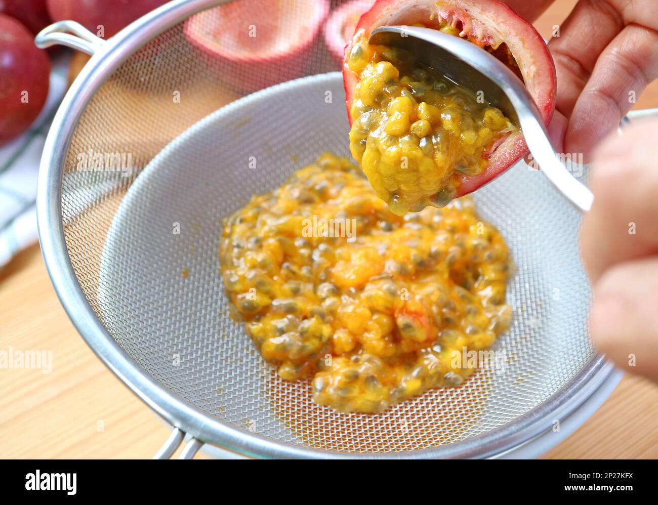 Spoon Scooping Passion Fruit Flesh into Strainer to Extract Liquid from ...