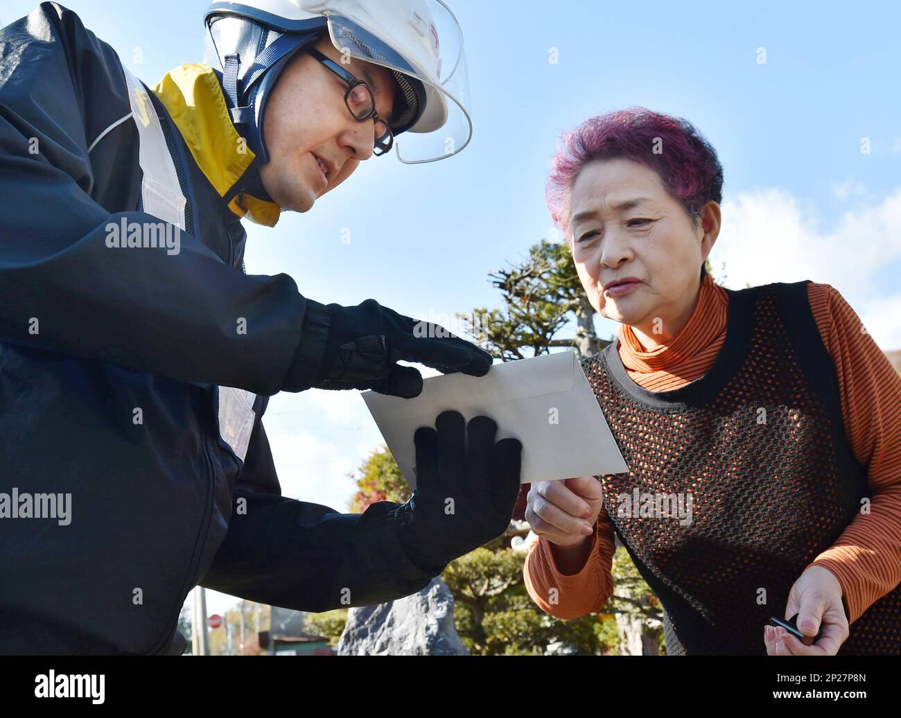 A postal delivery person hands an envelope containing a notification ...