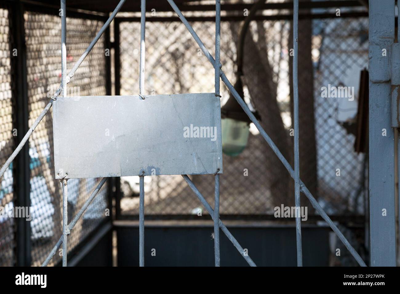 Metal blank sign on the prison type gray bars. Place for text on an ...