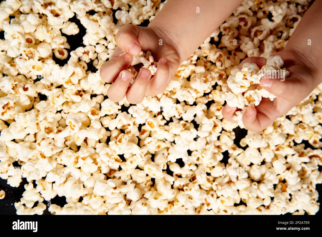 Children's hands are picking up popcorn. Flat lay . The concept of a ...