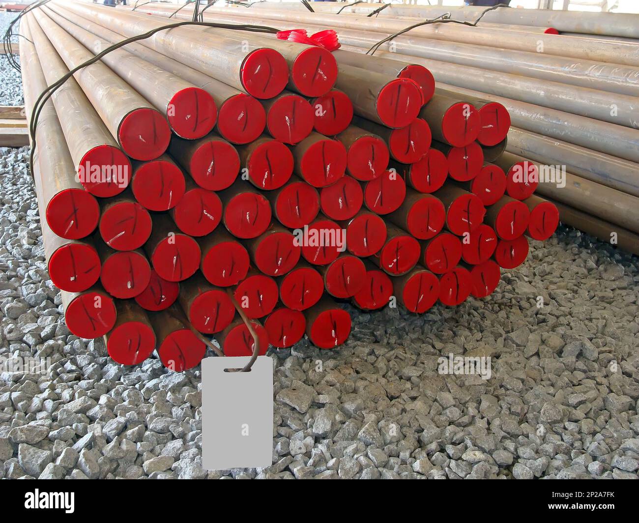 Stacking of seamless steel pipes at the construction site. Red plugs on ...