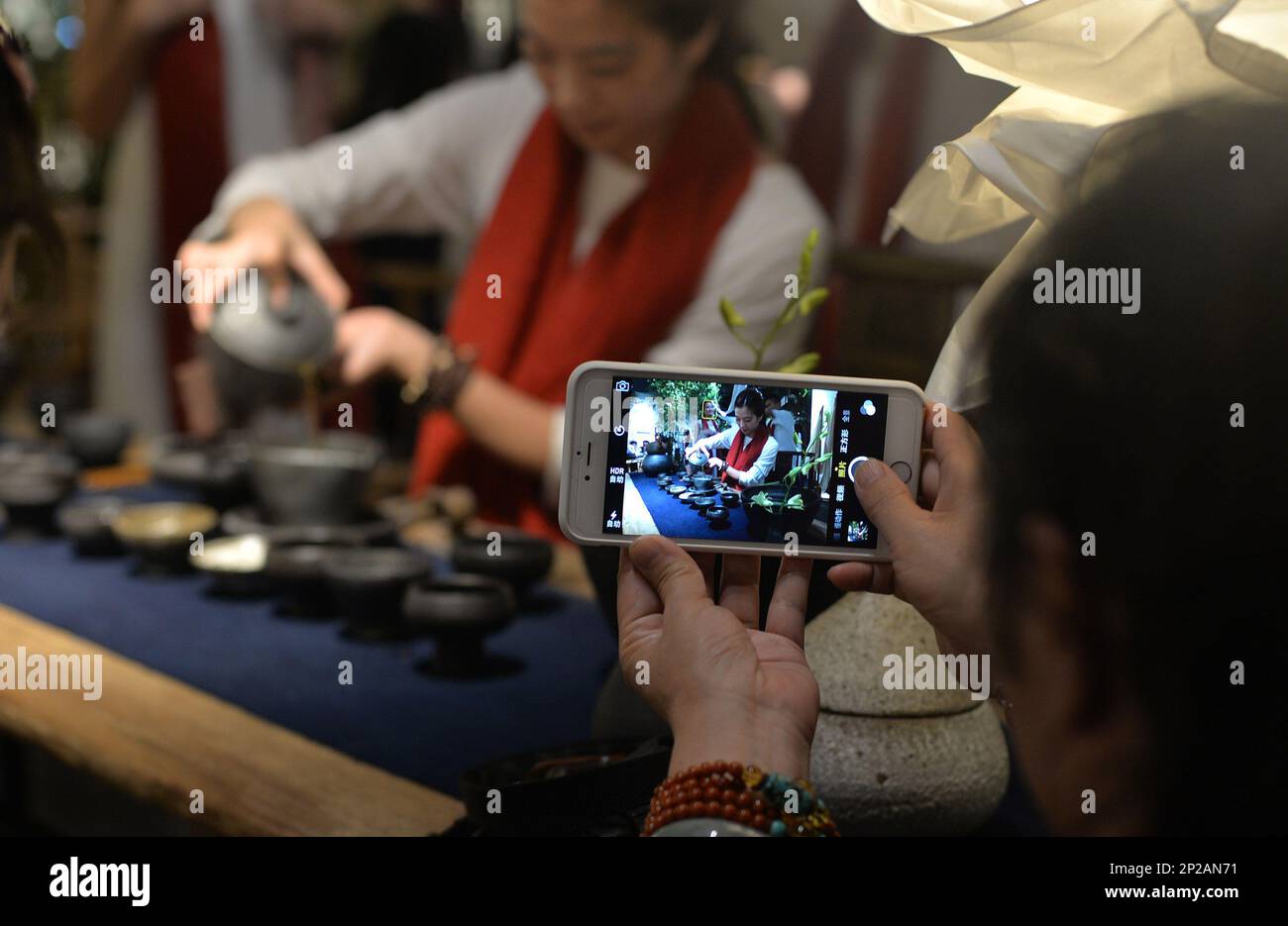 A visitor takes pictures of a tea specialist making tea with Yingjing ...