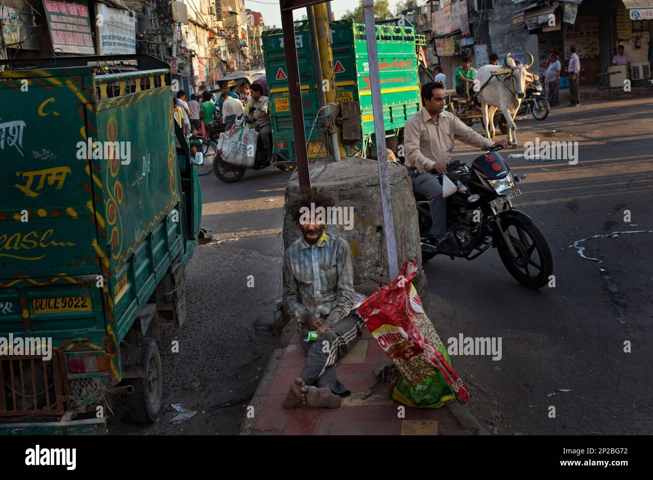 A homeless Indian man sits at a traffic intersection in the morning in ...