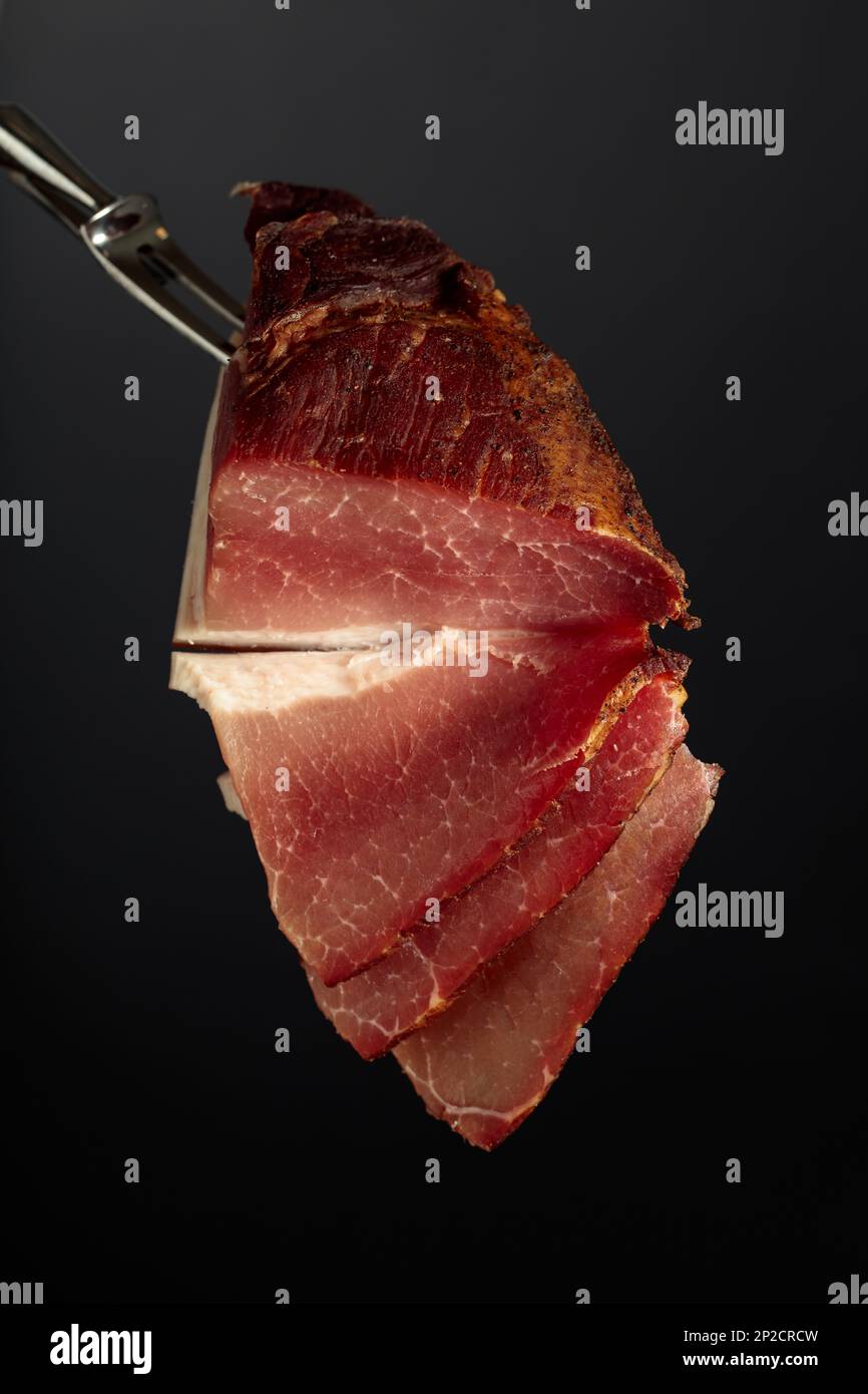 Dry-cured pork fillet on a black background Stock Photo - Alamy