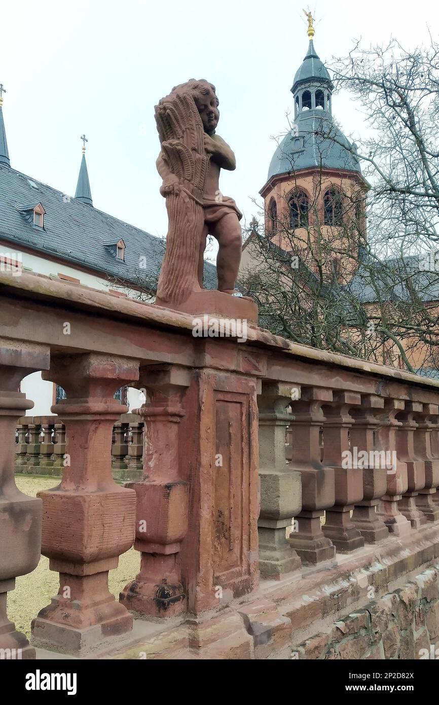Stone-carved balustrade, topped by sculpture of a putto holding a sheaf ...