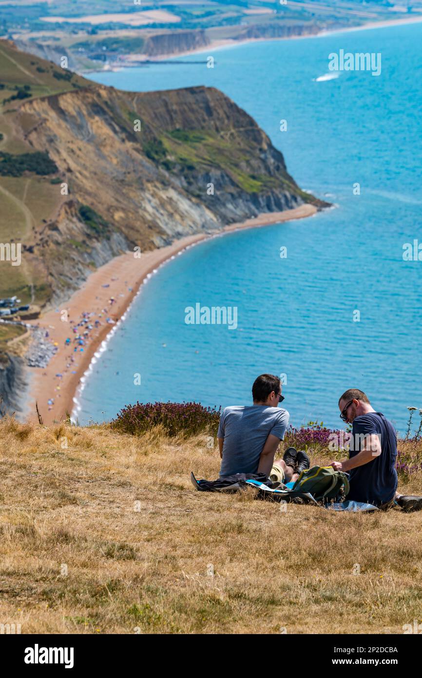 Couple of men resting on top of Golden Cap, in Summer, Jurassic coast ...