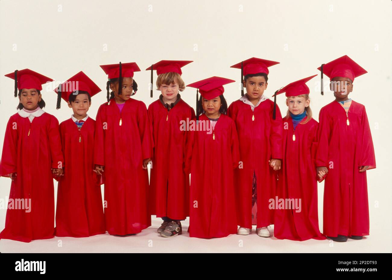 Row of children of different ethnicities, all wearing red and gowns ...