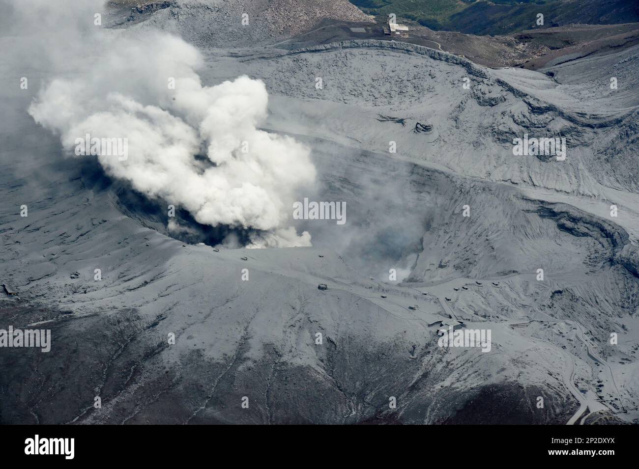 Volcanic smoke rises from Mount Aso with its mouth covered with gray ...