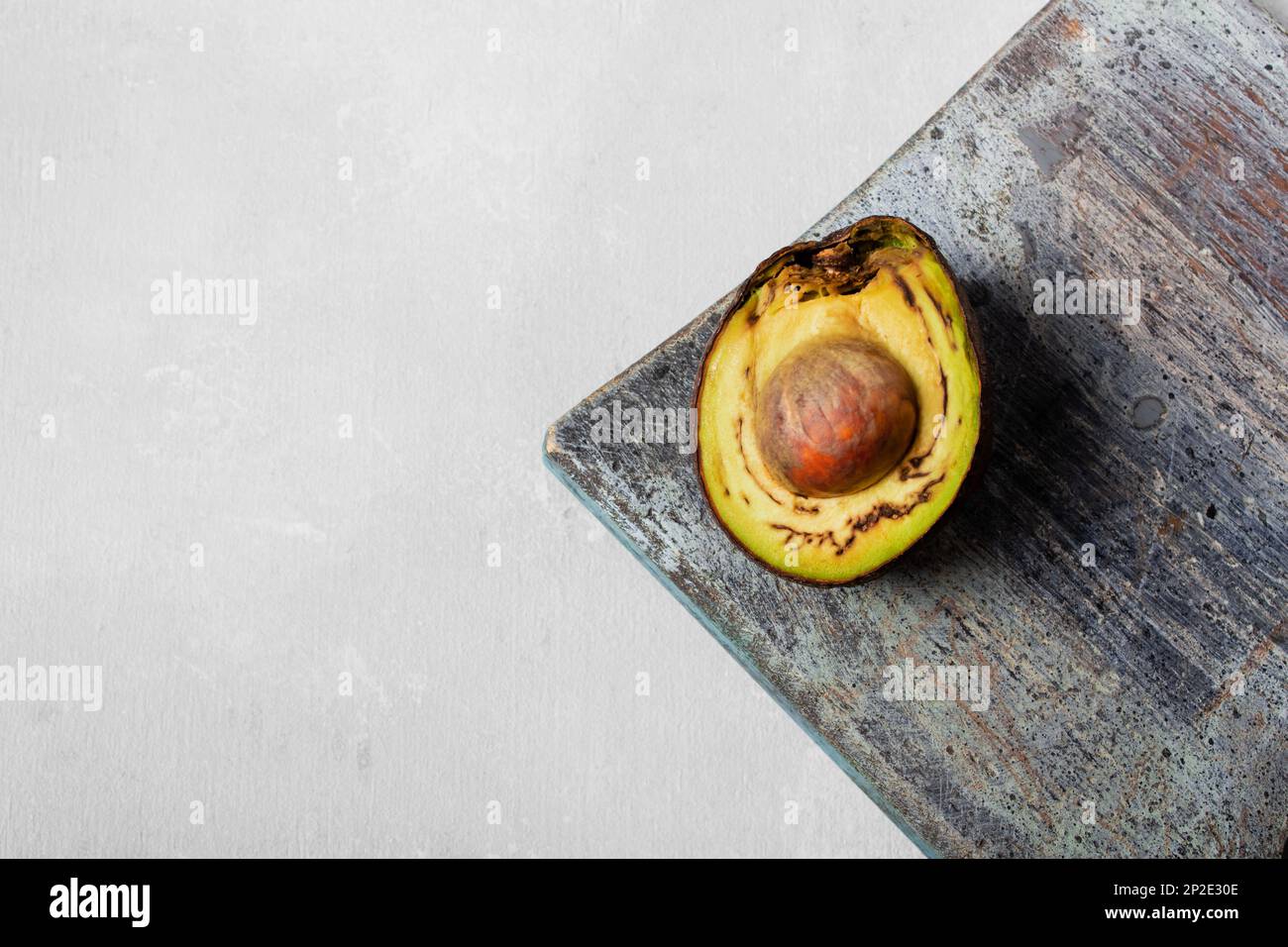 Rotten avocado, overriped, bad avocado on cutting board. Half sliced ...