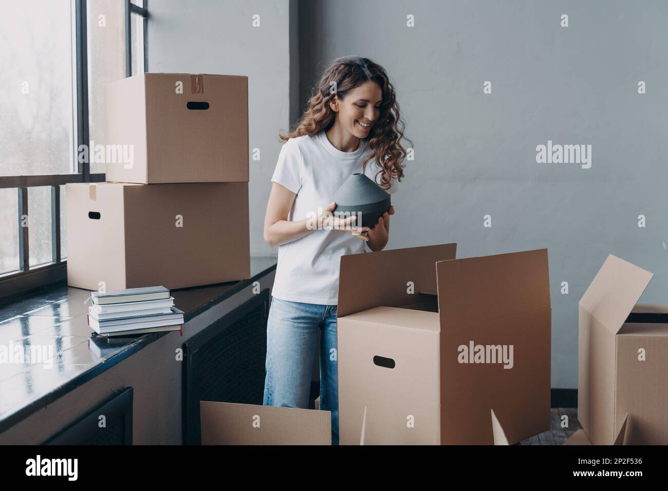 Happy homeowner young hispanic girl unpack box with belongings at new ...