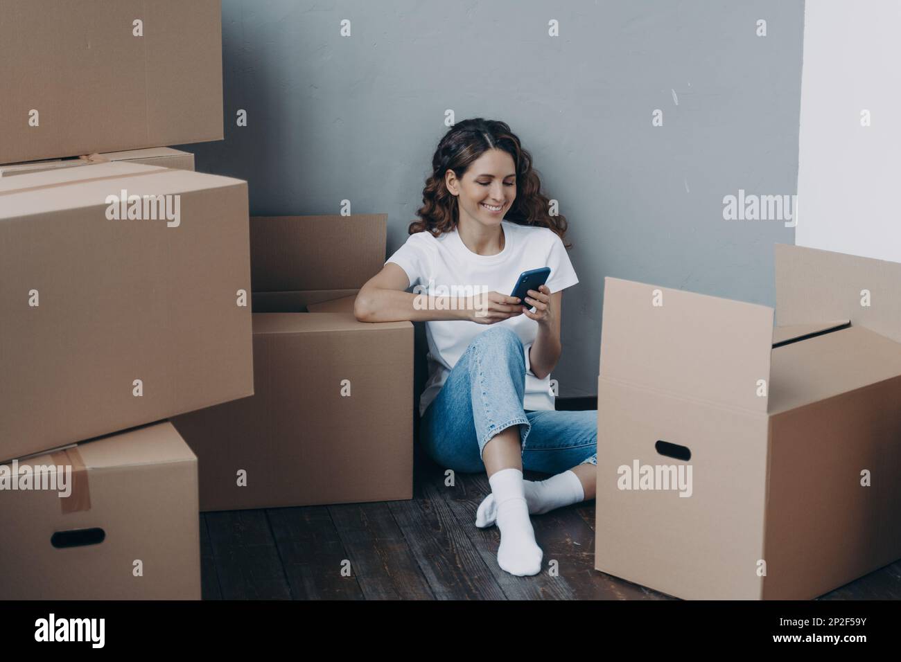 Happy latina female uses mobile phone apps, choosing moving service ...