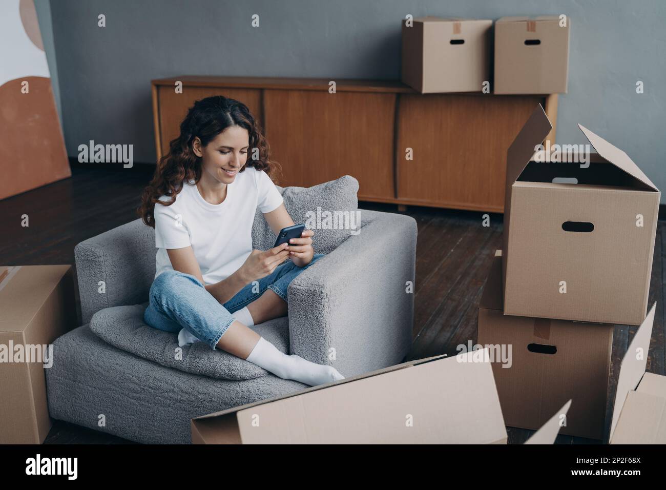 Smiling girl choosing mover online, using mobile phone app, sitting ...