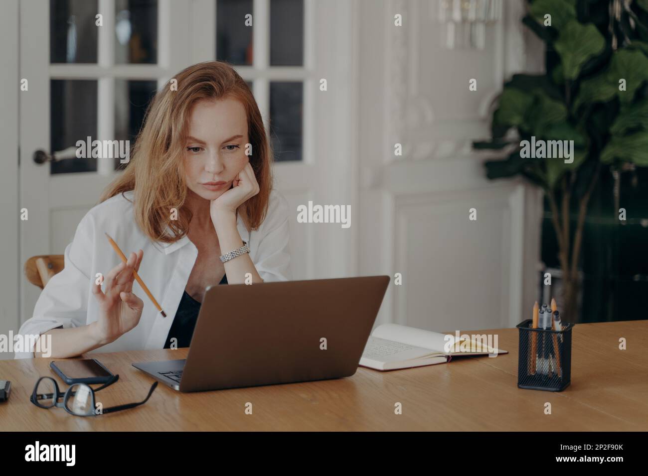 Puzzled female employee or student, sitting at work desk with laptop ...