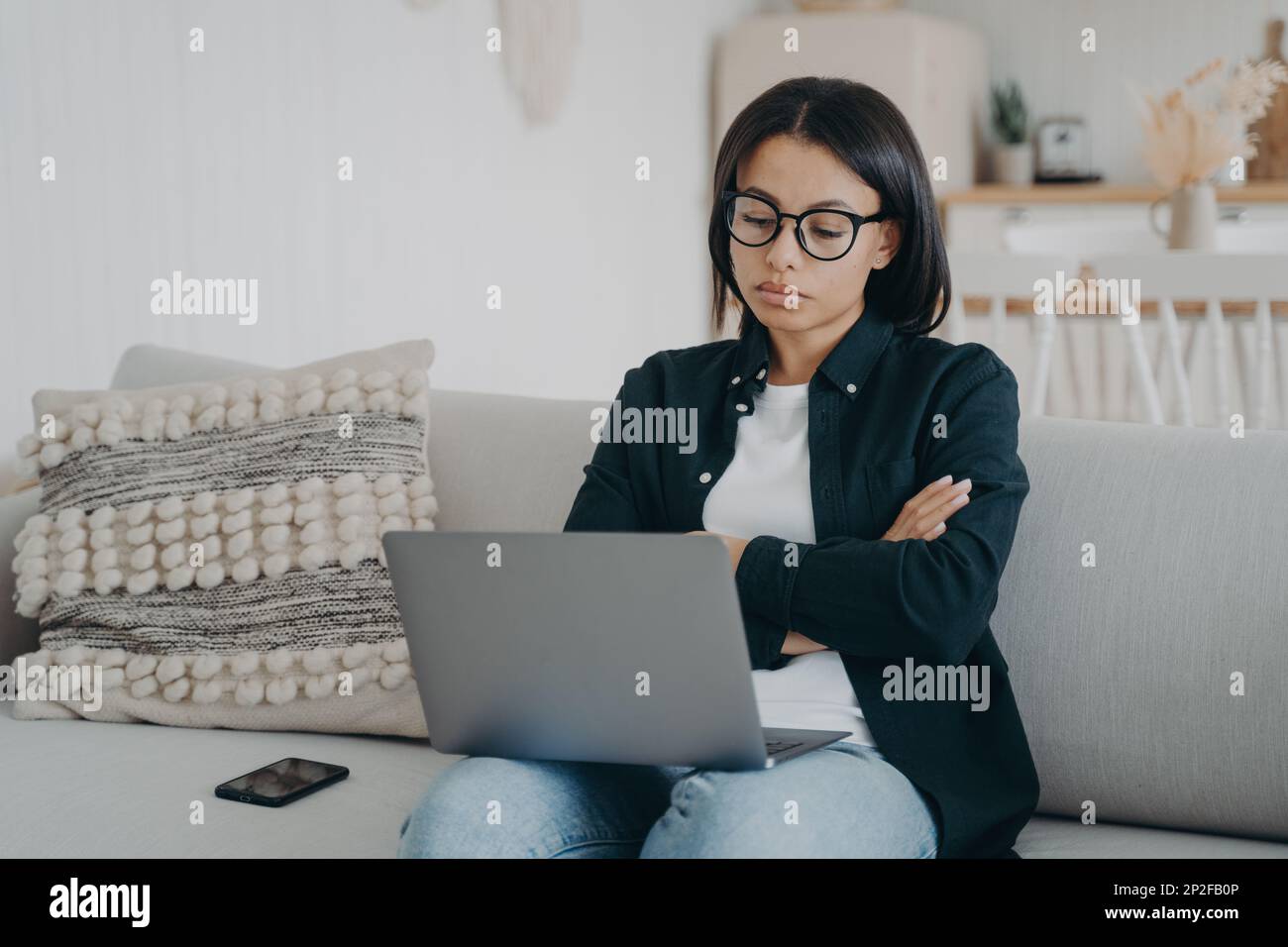 Skeptical businesswoman working on laptop reading email, crossed arms ...