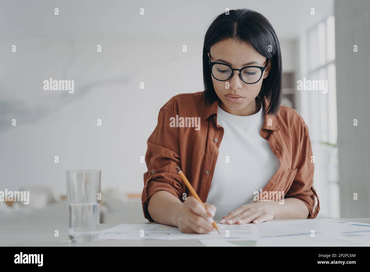 Focused Businesswoman In Glasses Works On Business Project Makes Notes Sitting At Workplace