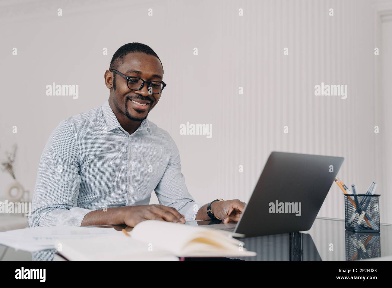 Pensive african american man wearing glasses working on laptop online ...