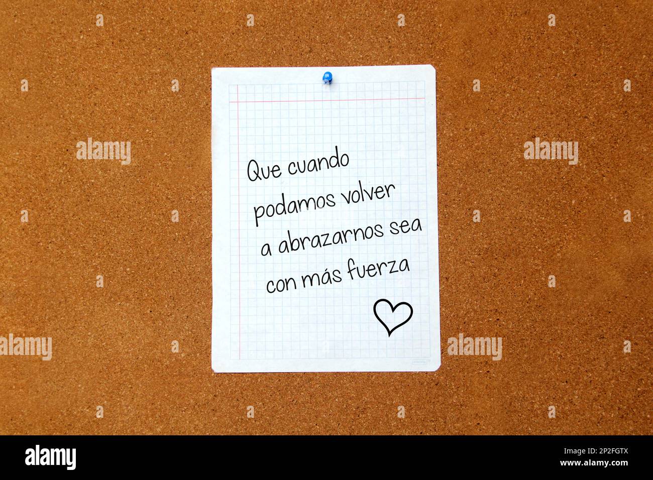 White note on cork board with message in Spanish "That when we can hug ...