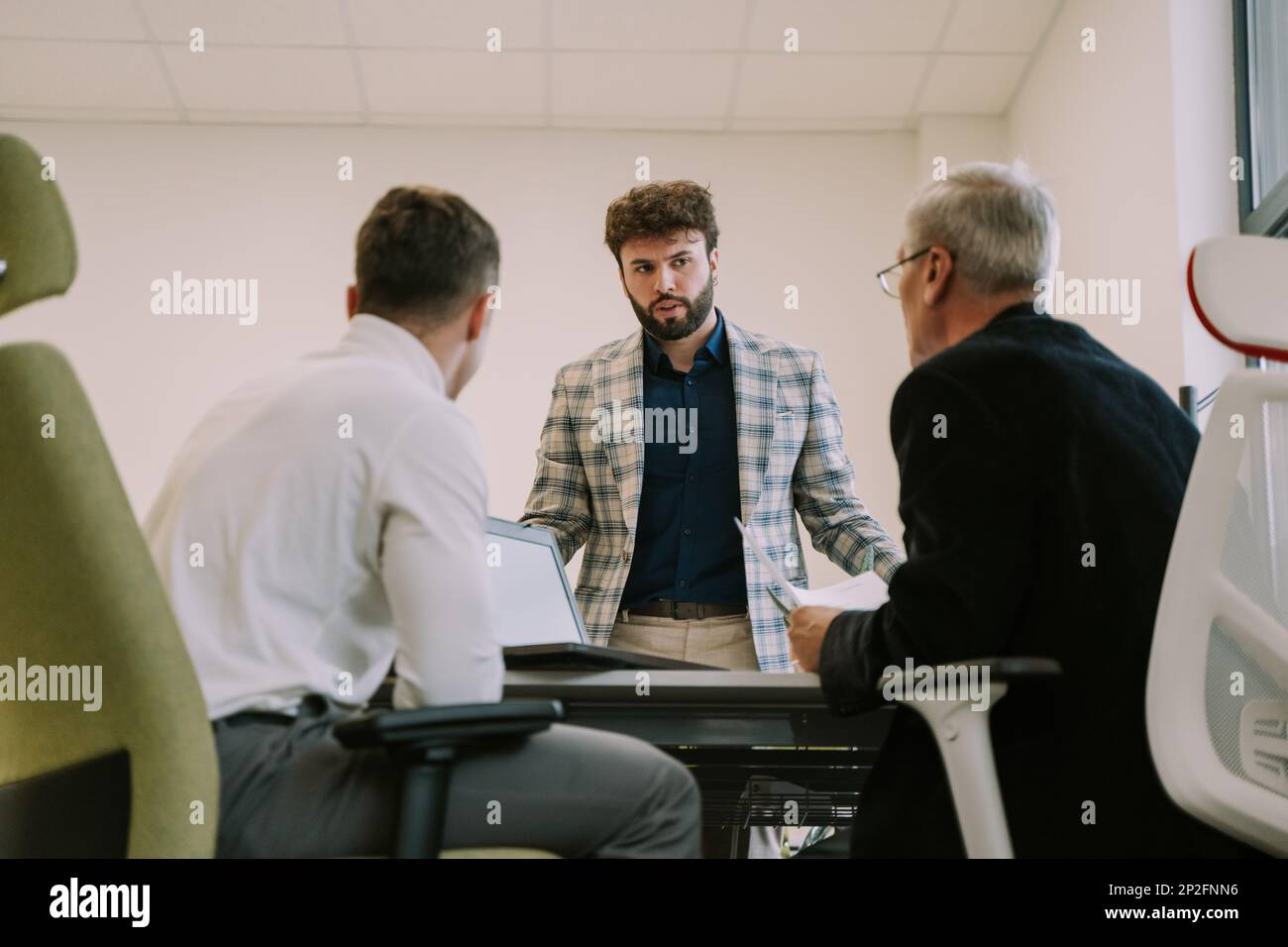 Disappointed and angry boss overlooking and warning his employees at ...