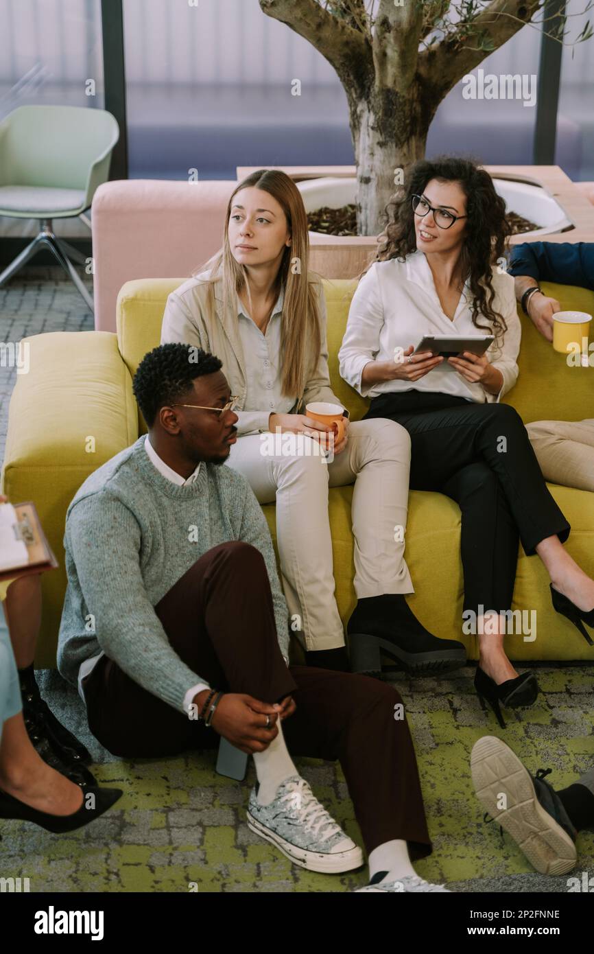 Two lovely girls listneing to their coworkers talking to them while ...