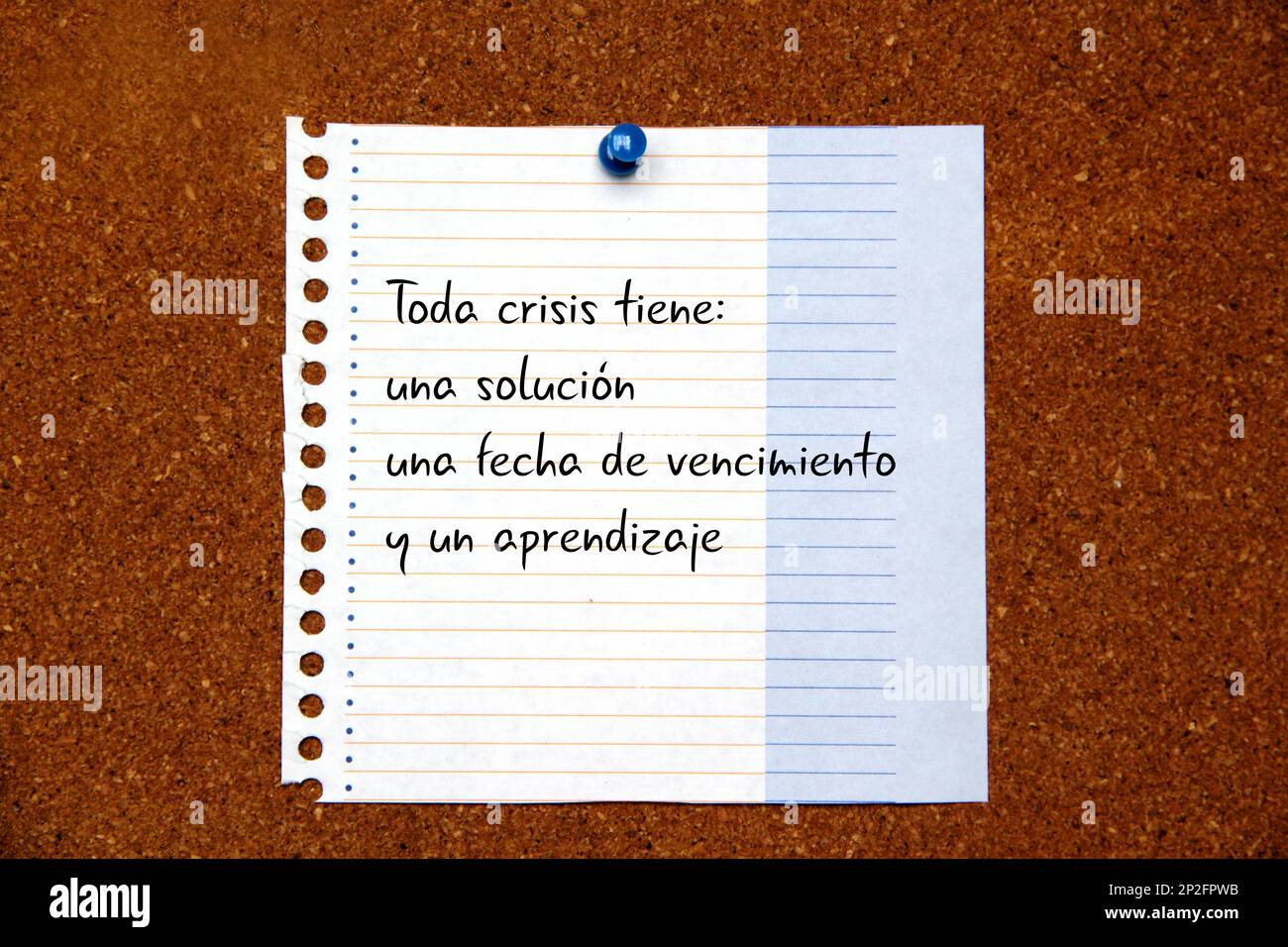 White note on cork board with message in Spanish language "Every crisis ...
