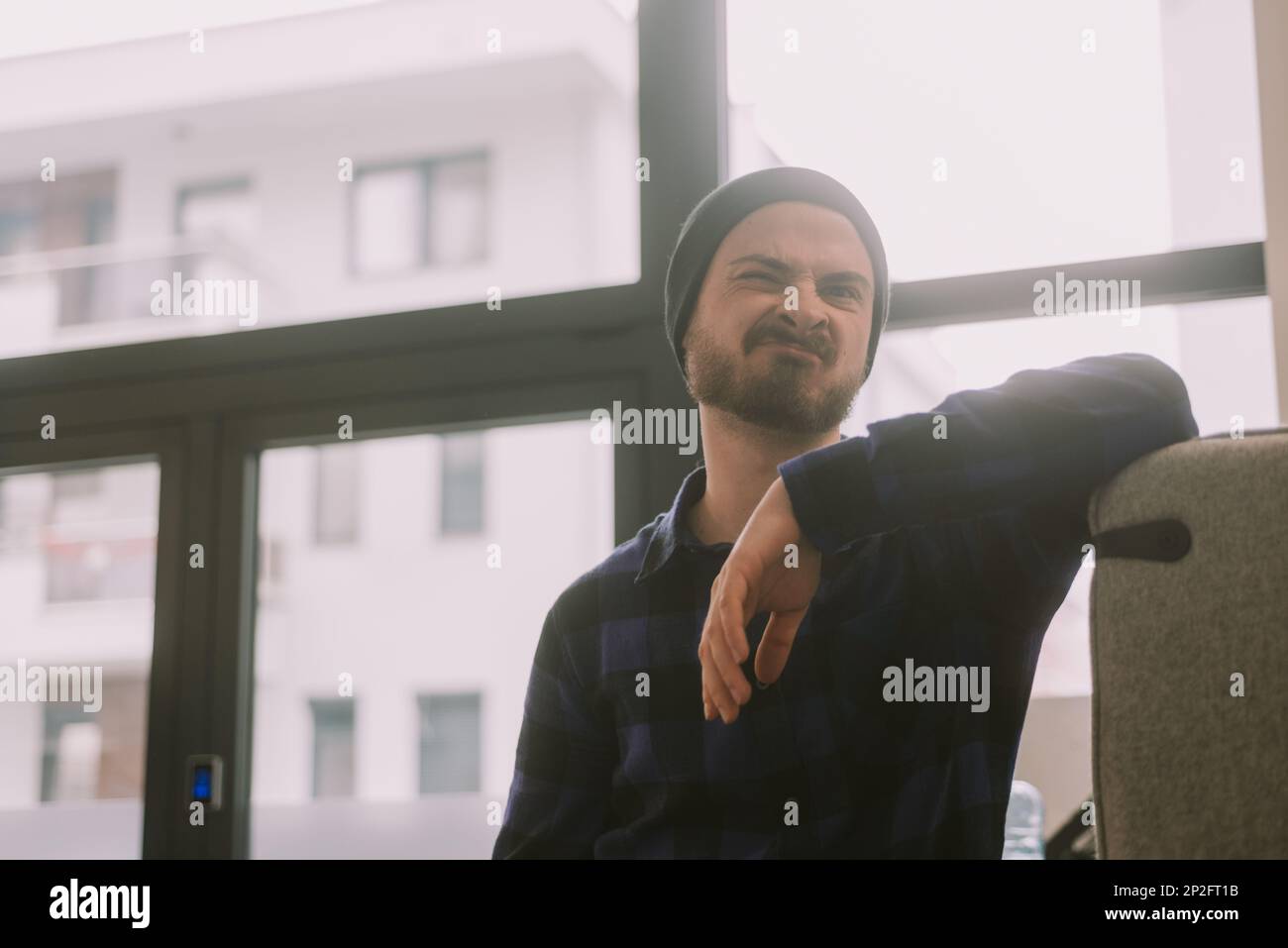 Handsome man making silly faces while standing infront of the window ...