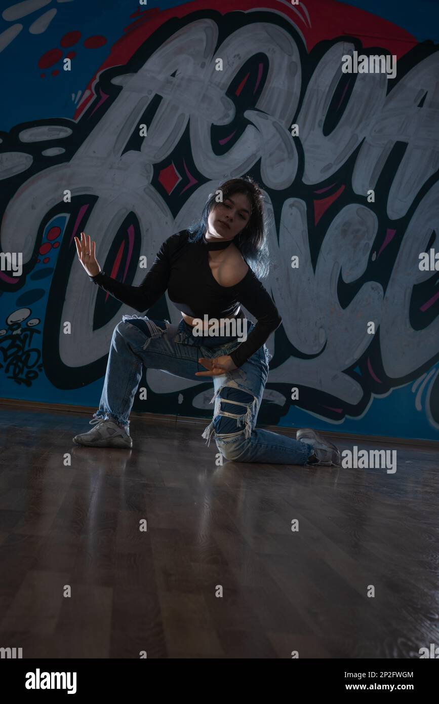 Female dancer in activewear squatting on the floor of modern dance ...