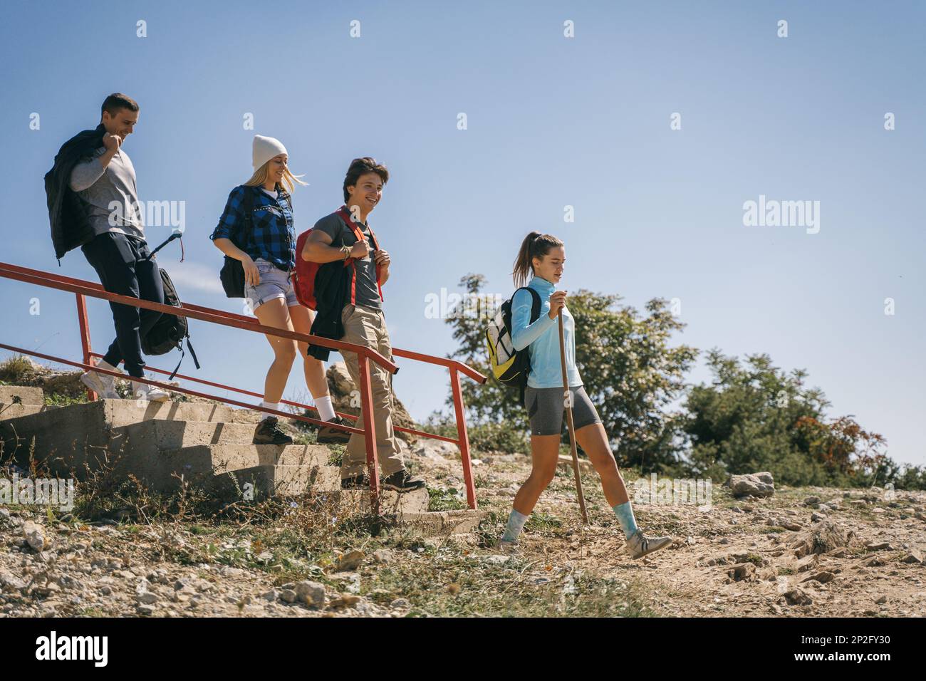 Hiking friends going down the stairs while smiling Stock Photo - Alamy