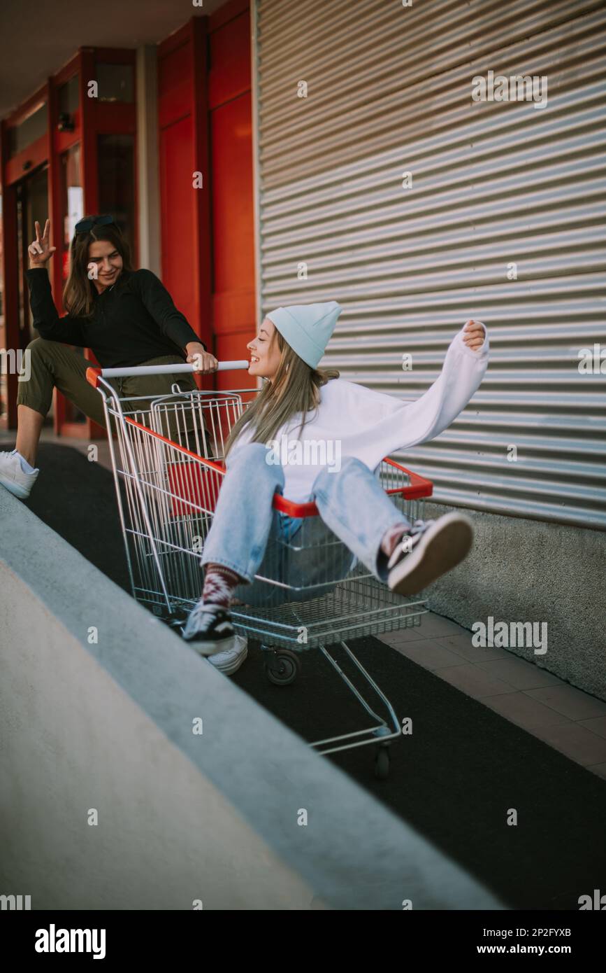 Two best friends having a fantastic time with a market cart at the ...