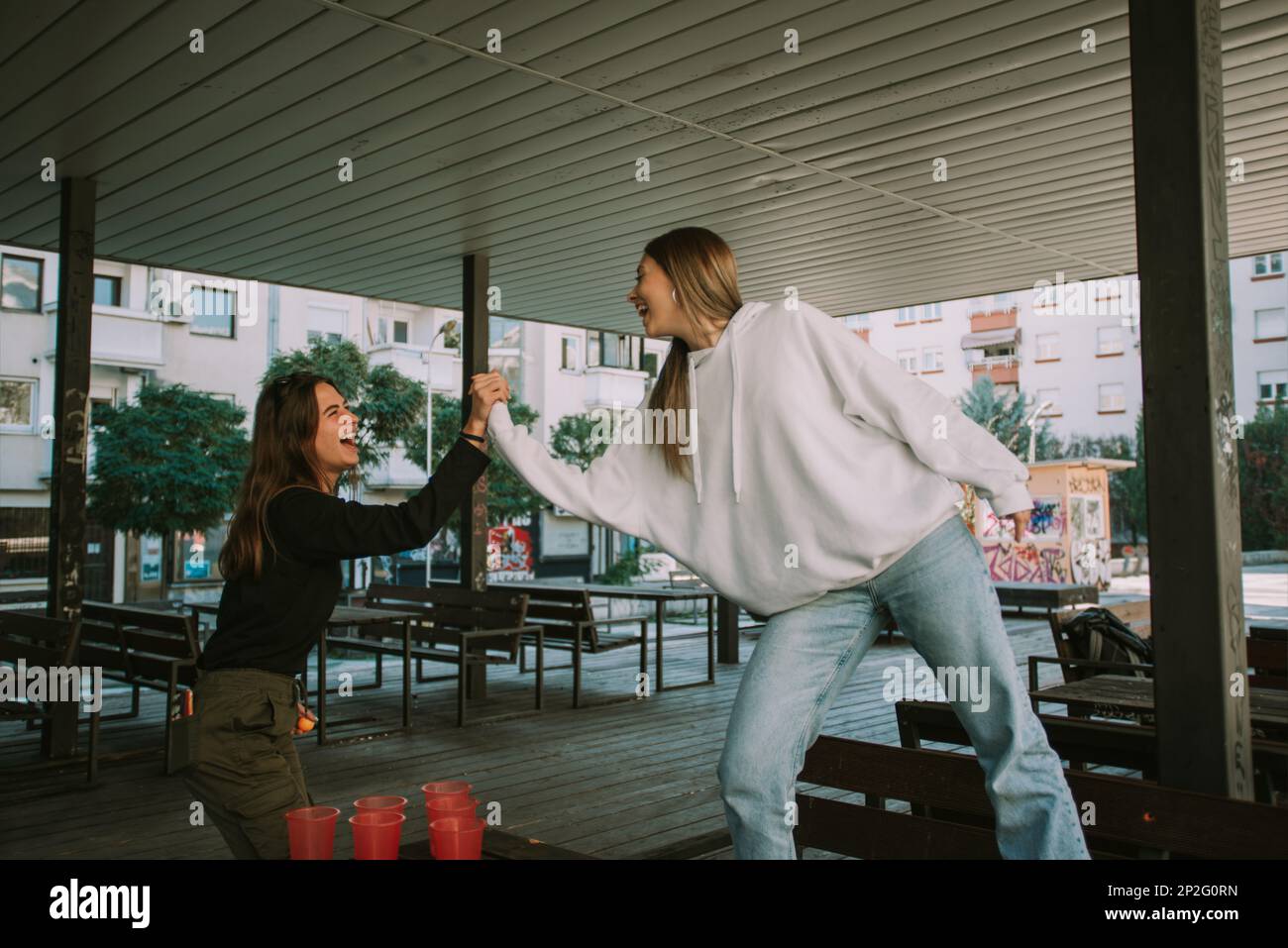 Twopretty best friends high fiving while standing at the wooden bench ...