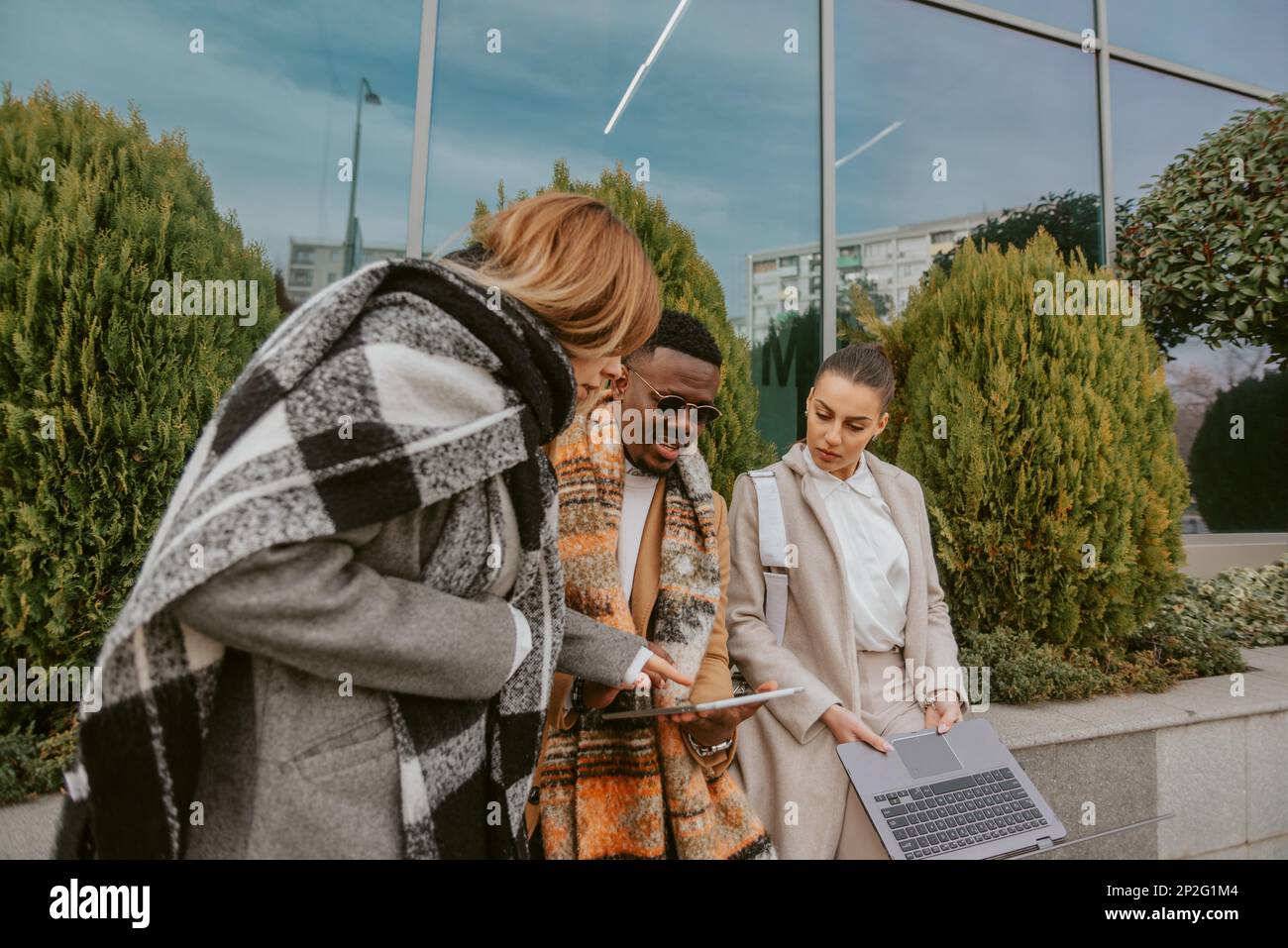Three business people talking while working outside in front of the ...