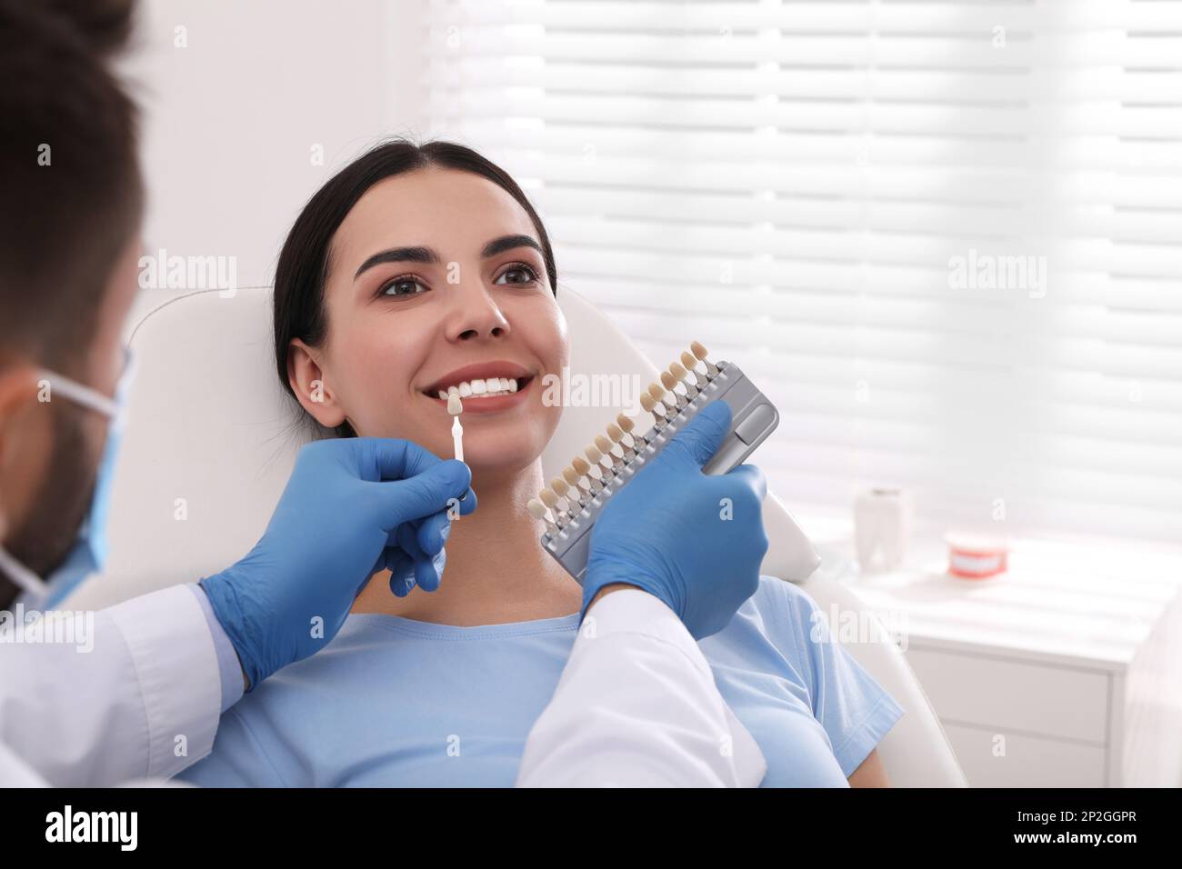 Dentist checking young woman's teeth color in clinic Stock Photo - Alamy