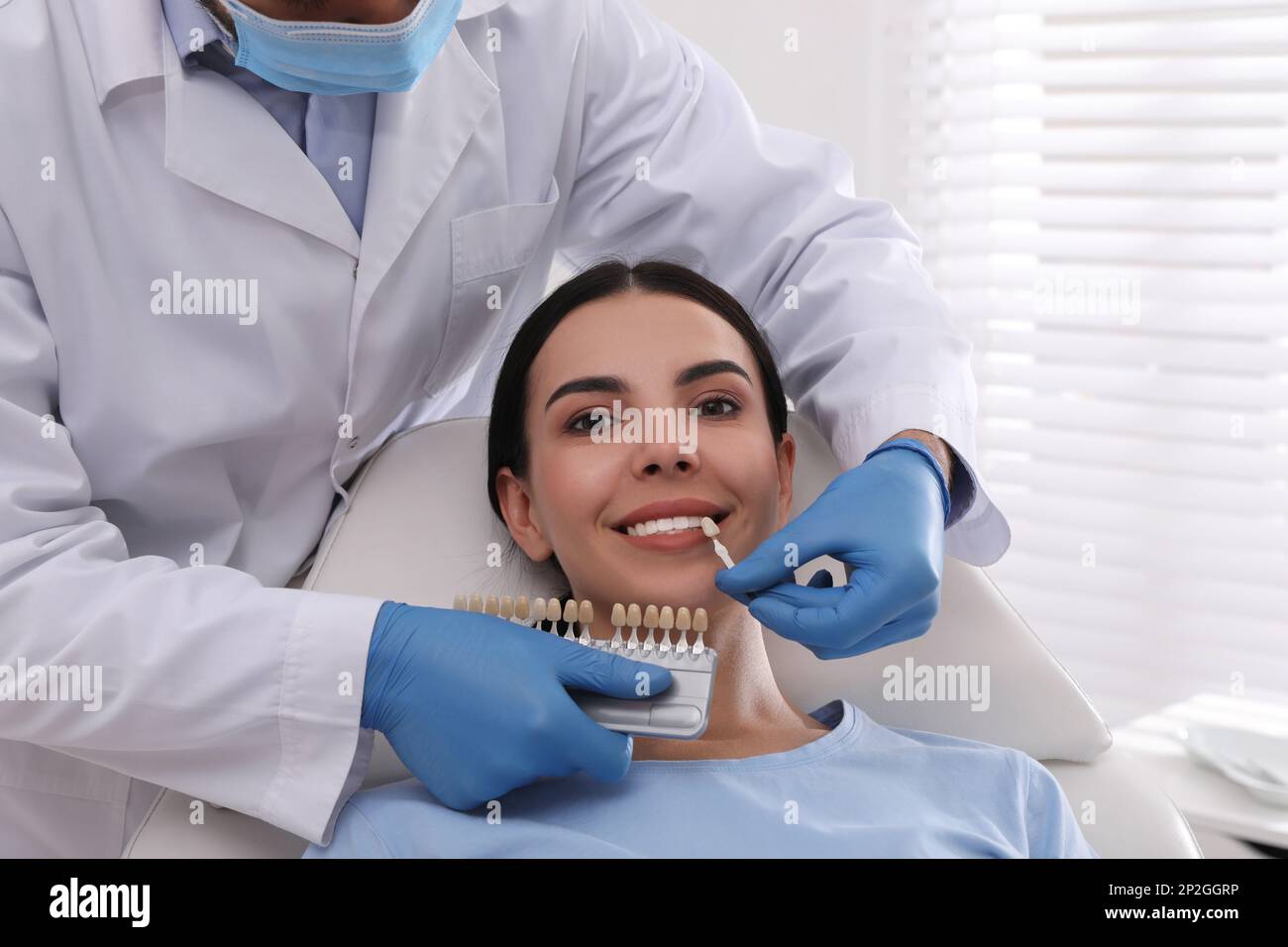 Dentist checking young woman's teeth color in clinic Stock Photo - Alamy