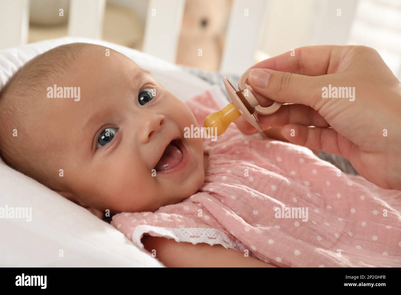 Mother giving pacifier to cute little baby in soft crib, closeup Stock ...