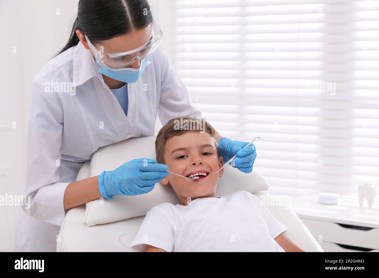Dentist examining little boy's teeth in modern clinic Stock Photo - Alamy